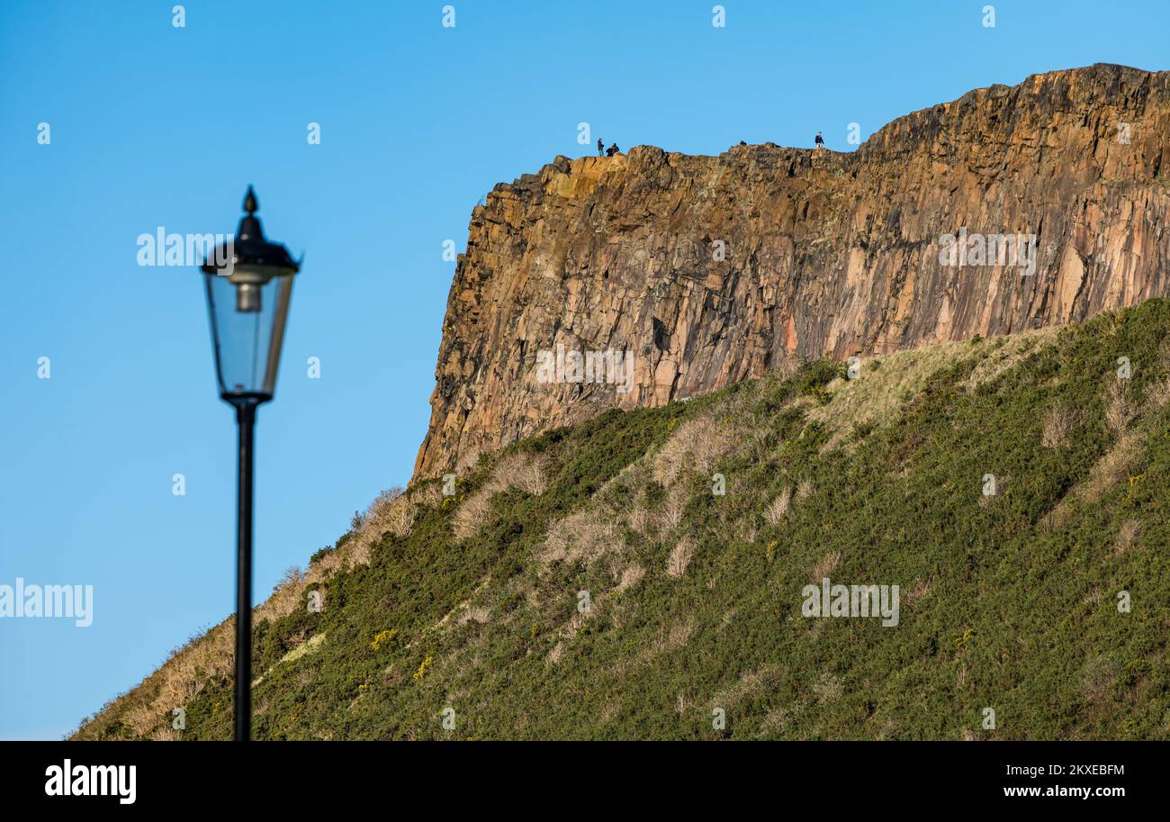 View of people clifftop ledge on Salisbury Crags, a rocky cliff in ...