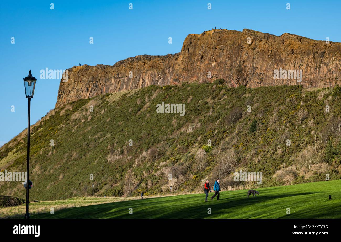 View of people clifftop ledge on Salisbury Crags, a rocky cliff in ...