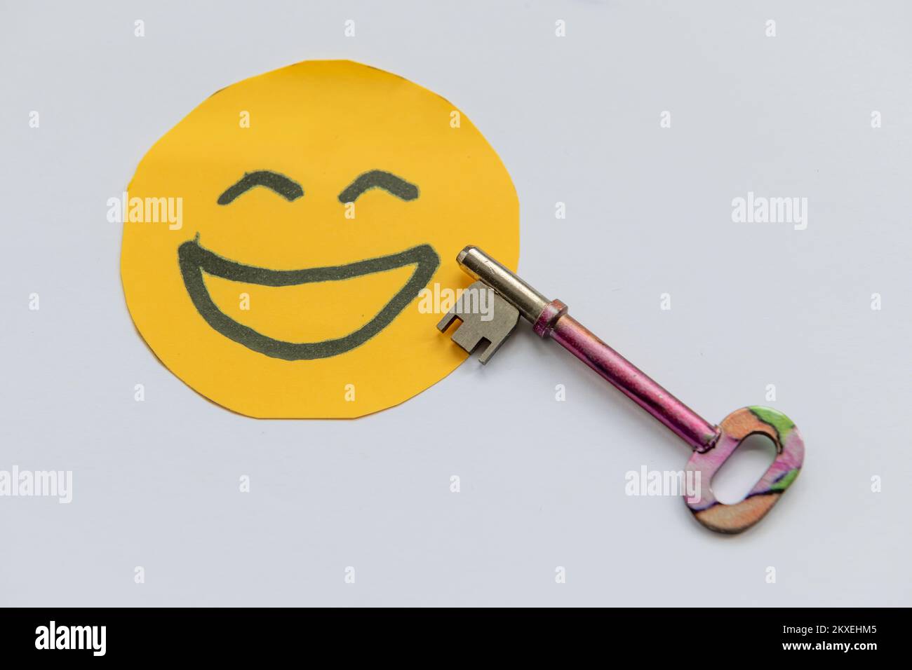 A key to happiness concept with a key and hand drawn happy face ...