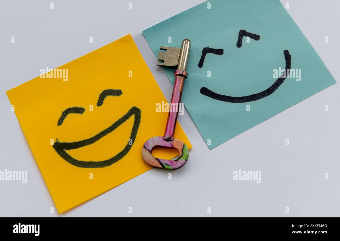 A key to happiness concept with a key and hand drawn happy faces ...