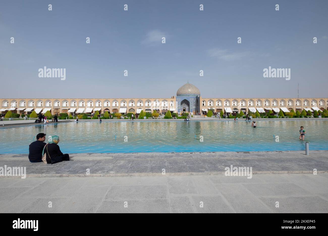 Muslim couple sitting in front of the Shah Mosque in the Naghsh e Jahan ...