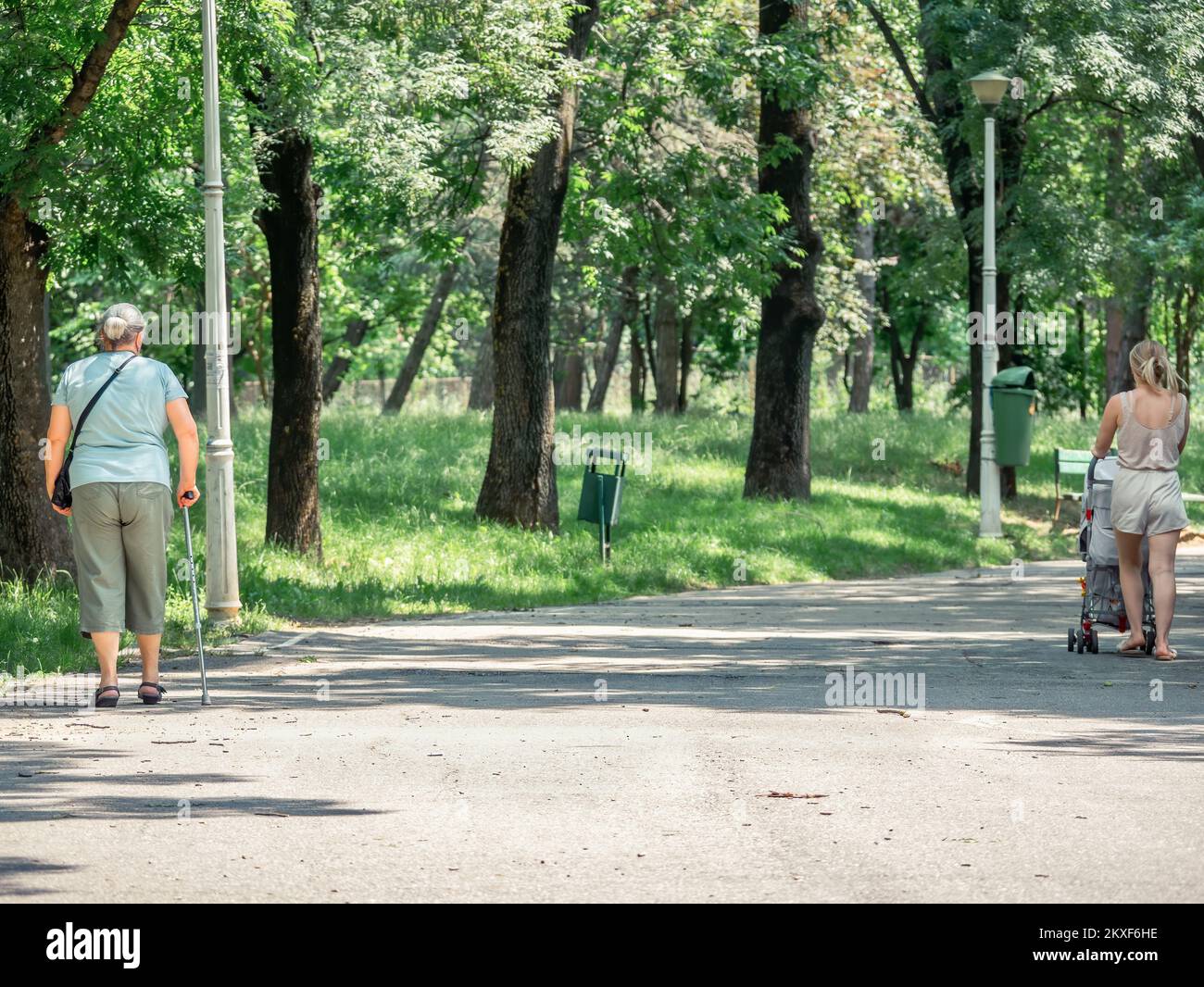 Old senior woman and a young woman pushing a Baby Stroller walking on ...
