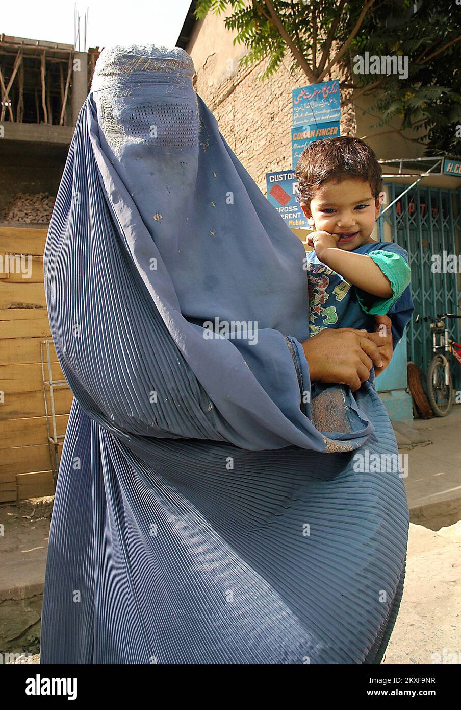 Kabul / Afghanistan: Woman dressed in a blue burqa holding a child ...