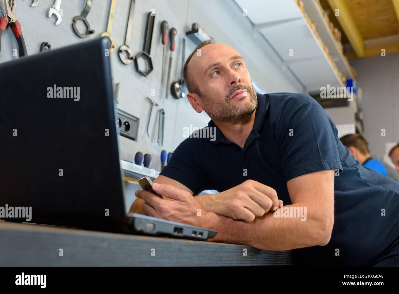 mechanic with laptop and smartphone in garage Stock Photo - Alamy
