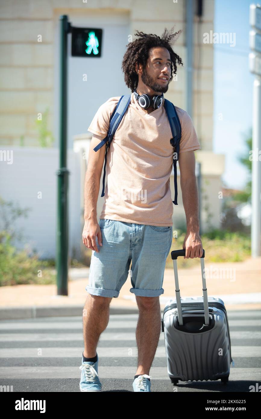 handsome man pulling his luggage across pedestrian crossing Stock Photo ...