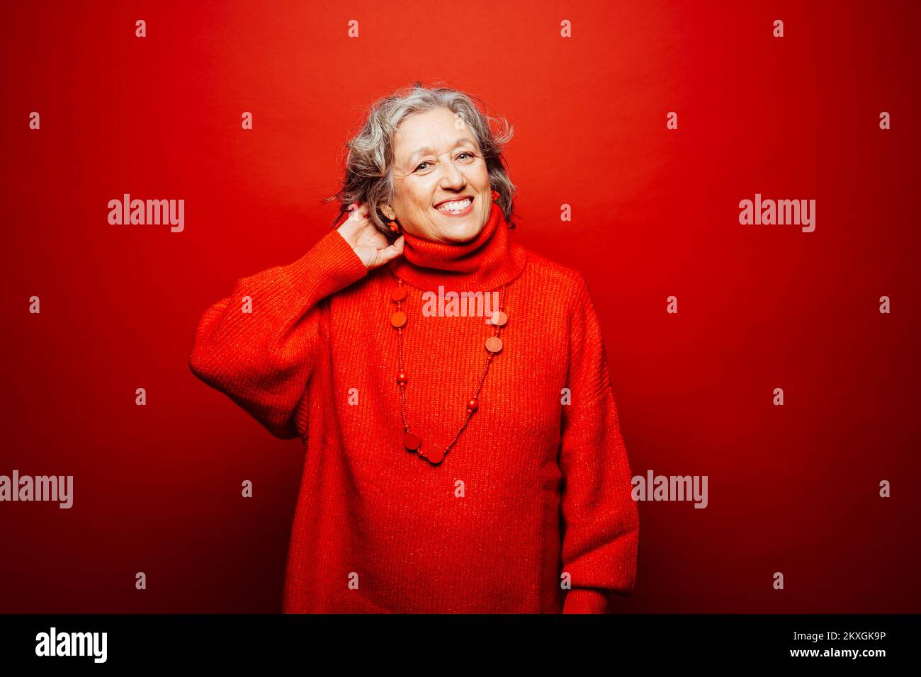 Senior smiling woman red clothes over a red background Stock Photo - Alamy