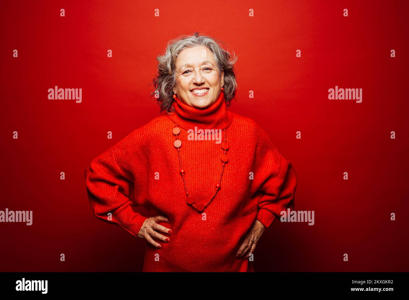 Senior smiling woman red clothes over a red background Stock Photo - Alamy
