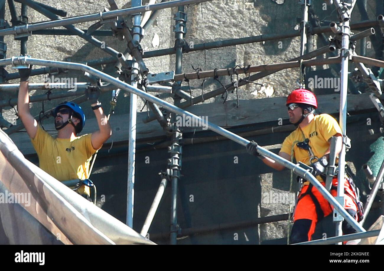 Workers repair a broken scaffolding that was destroyed by the fall of ...