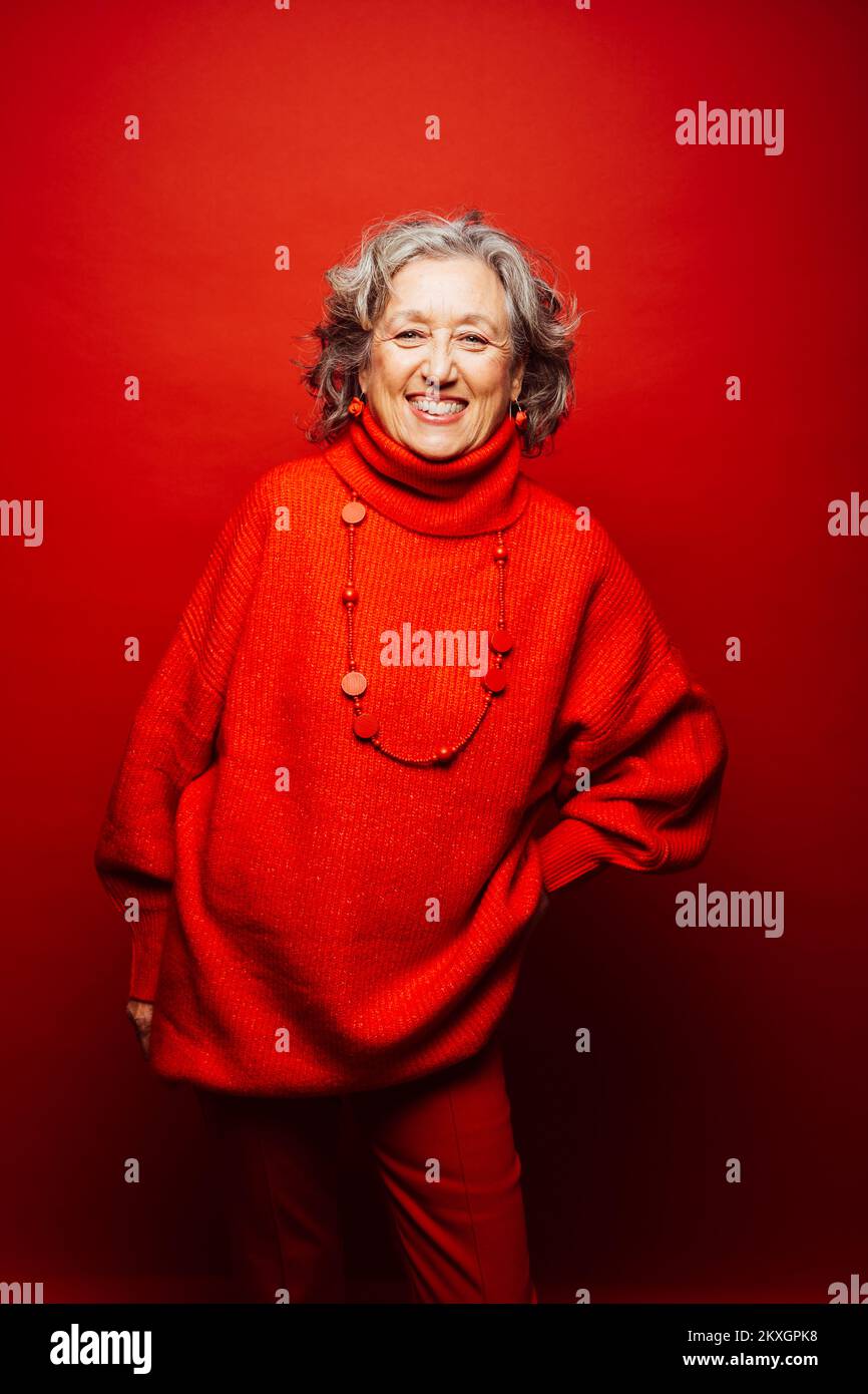 Senior smiling woman red clothes over a red background Stock Photo - Alamy