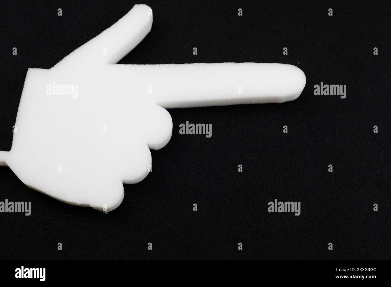 a hand made of foam rubber with an index finger on a black background ...