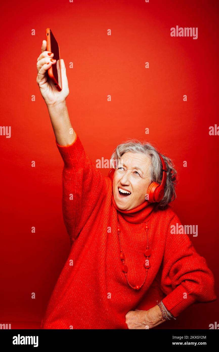 Senior woman wearing red clothes, with red headphones and red ...