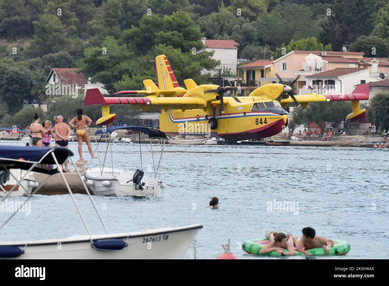A tourists looks on as a Croatia fire-fighting plane swoops down on the ...