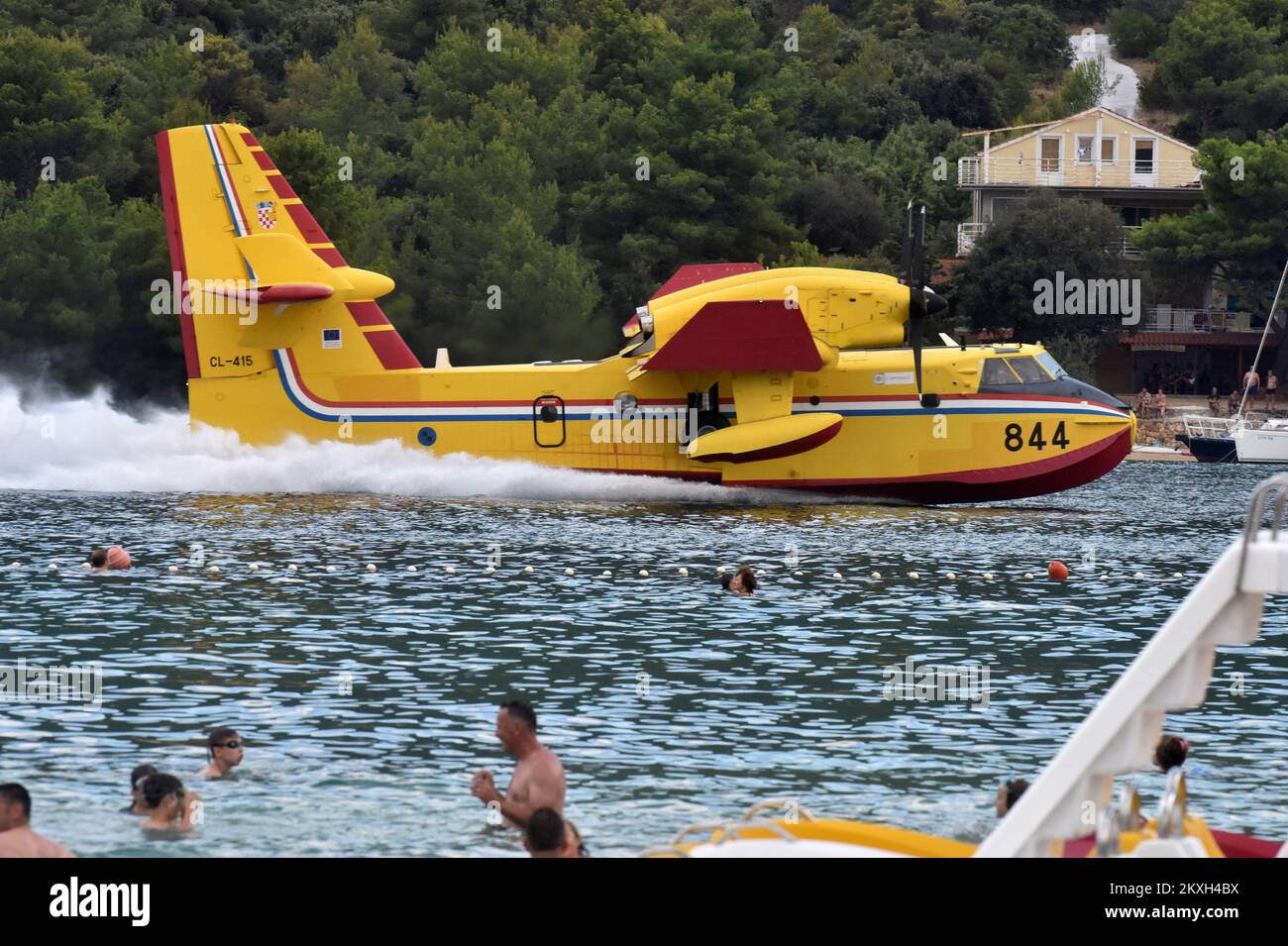 A tourists looks on as a Croatia fire-fighting plane swoops down on the ...
