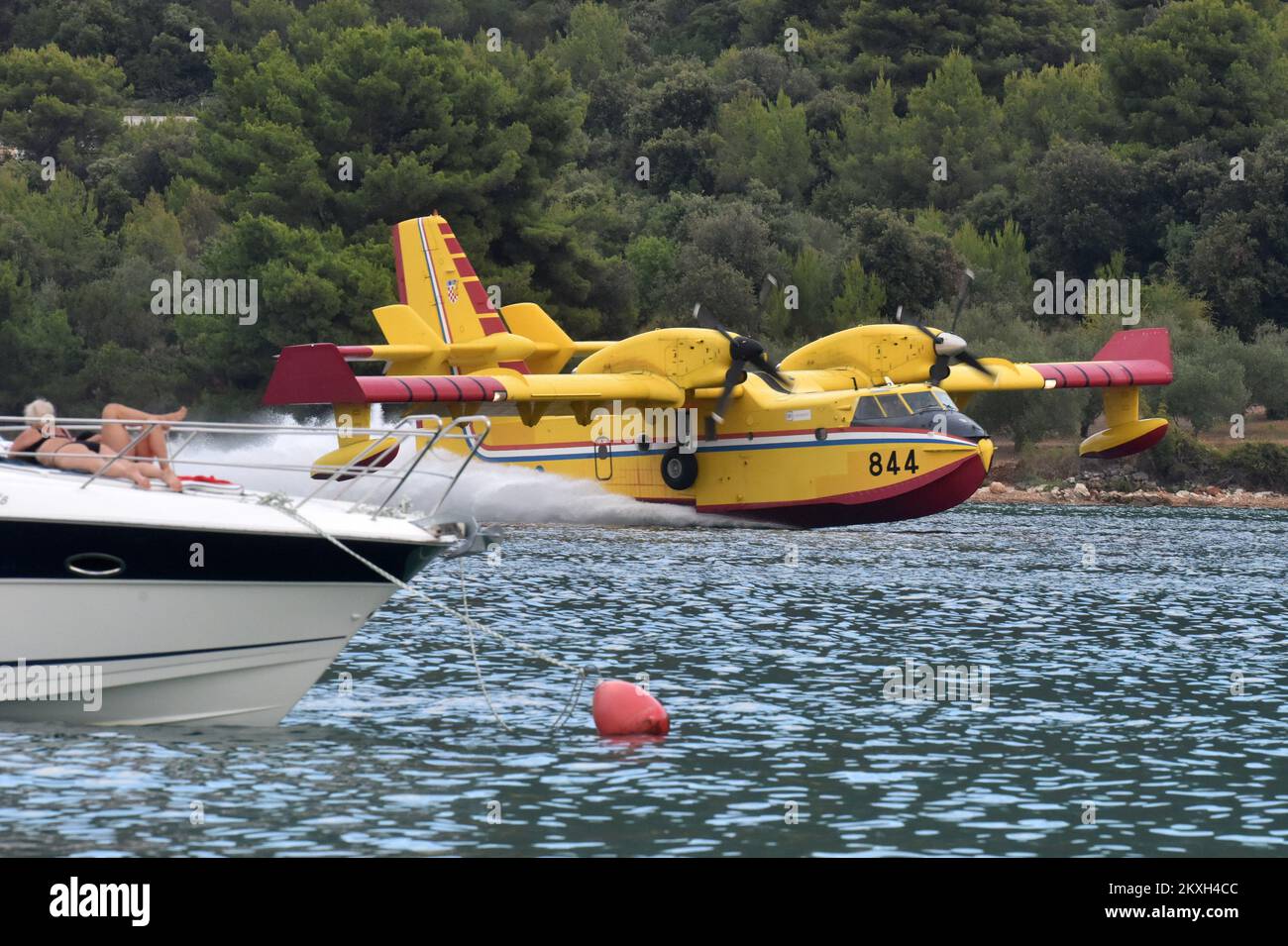 A tourists looks on as a Croatia fire-fighting plane swoops down on the ...