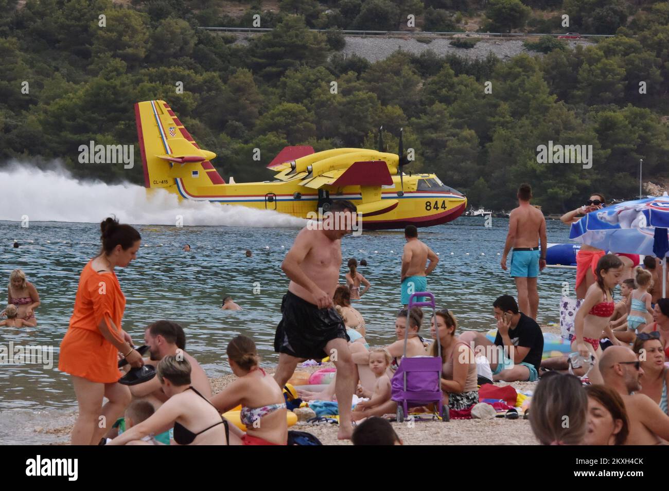 A tourists looks on as a Croatia fire-fighting plane swoops down on the ...