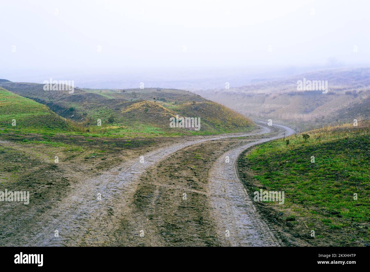 dirt muddy road wet Puddle countryside autumn fall green grass steppe ...