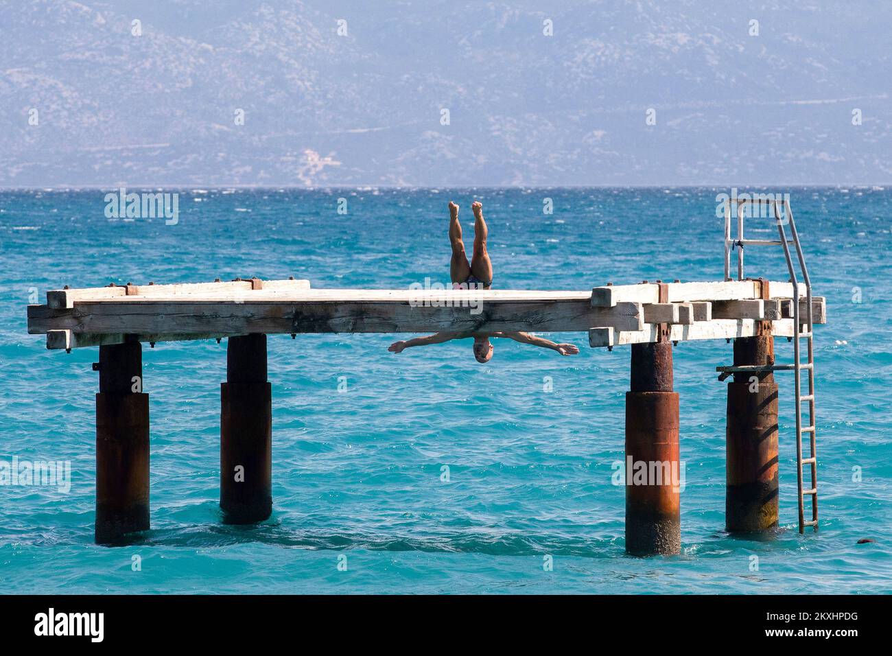 Man is seen jummping in the sea on the beach in Baska on island Krk ...