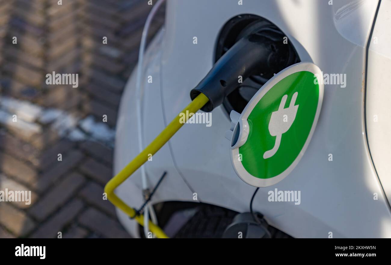 A picture of a small electric car being charged on the street Stock ...