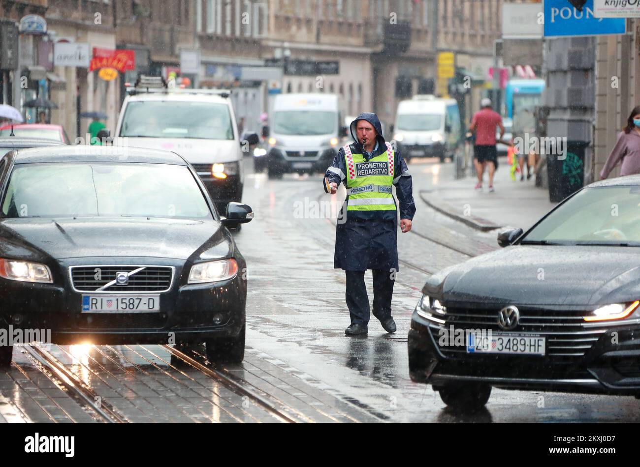 A traffic police officer in the rain controls traffic on Ilica Street ...