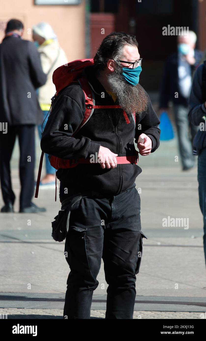A man with a backpack and a protective mask on his face is waiting for ...