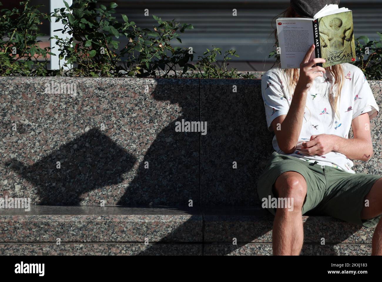 A young man seen reading a book in the sun in Zagreb, Croatia on ...