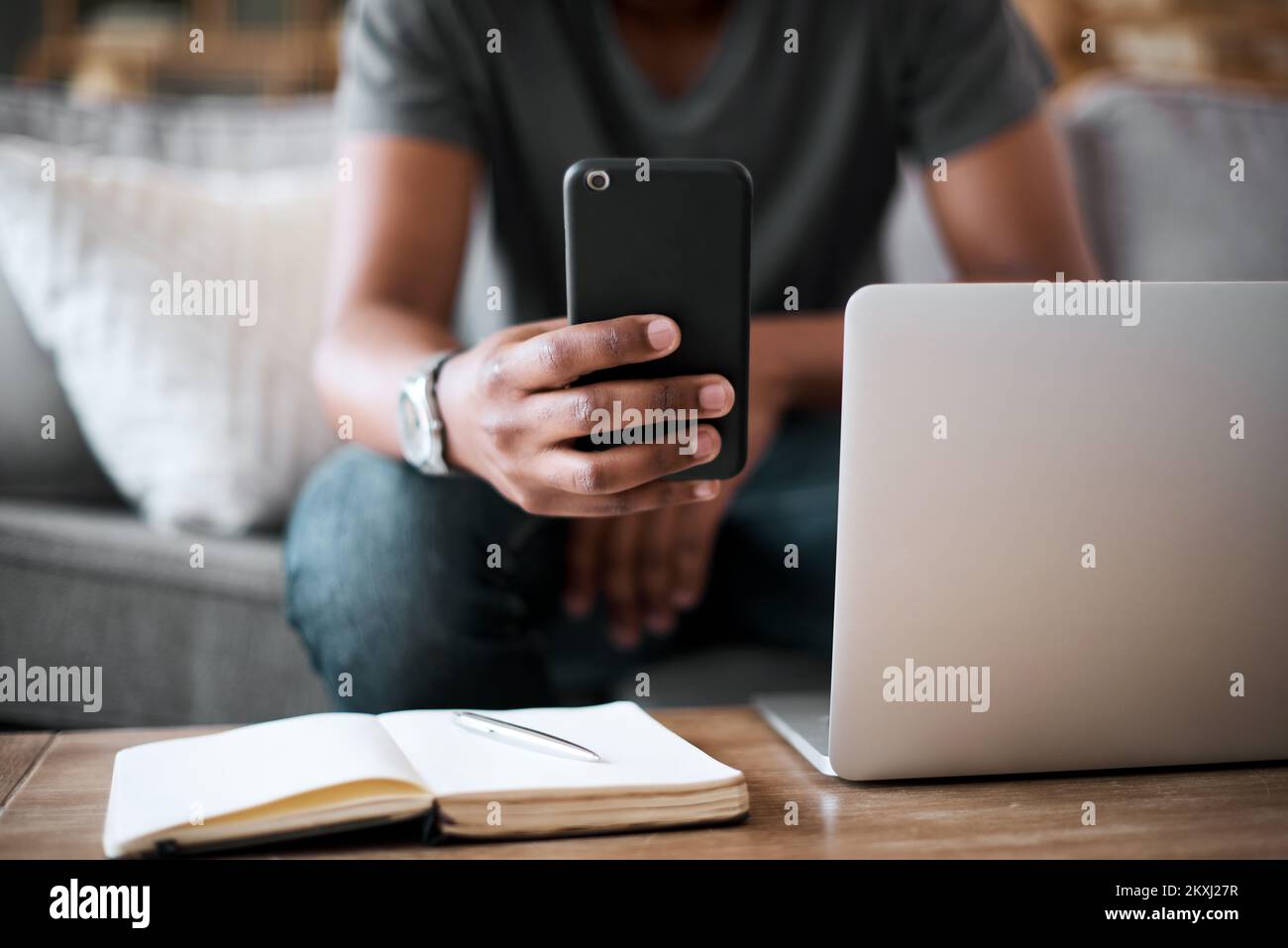 Hands, phone and man with laptop planning on sofa in communication or ...