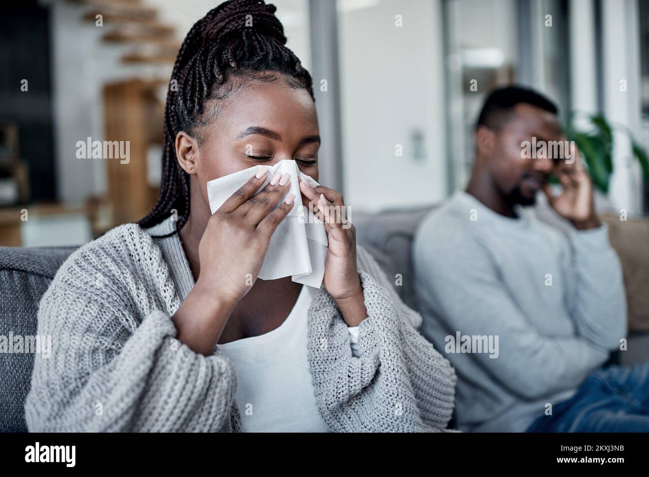 Young, sick and ill woman blowing her nose with tissues while sitting ...