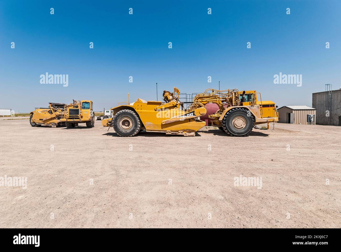 Two large segmented Caterpillar heavy equipment tractors are parked in ...