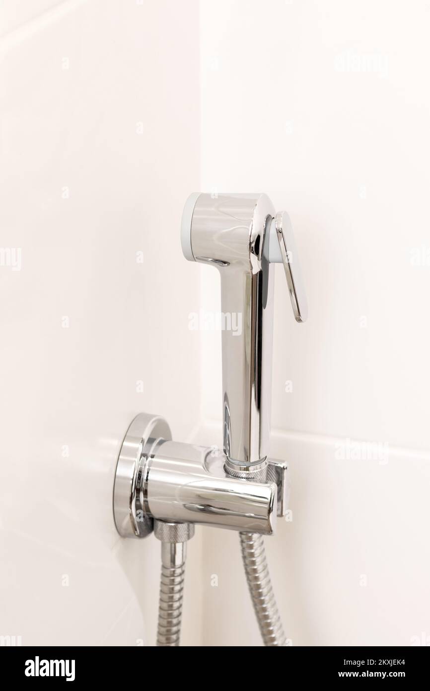 Hygienic shower on white tile wall. Details in bright modern bathroom ...