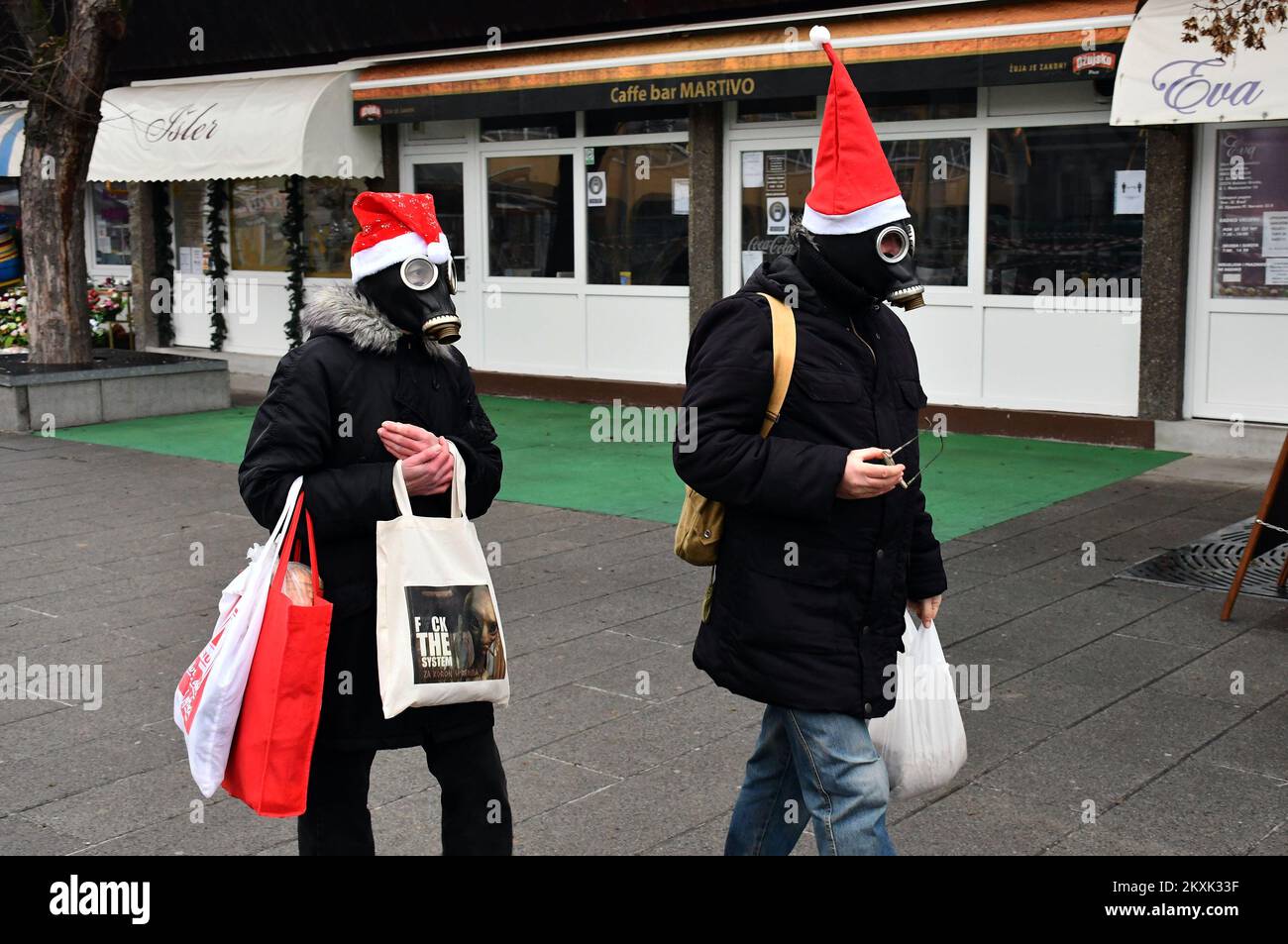 Citizens walk with Santa hats and gas masks as protection against ...