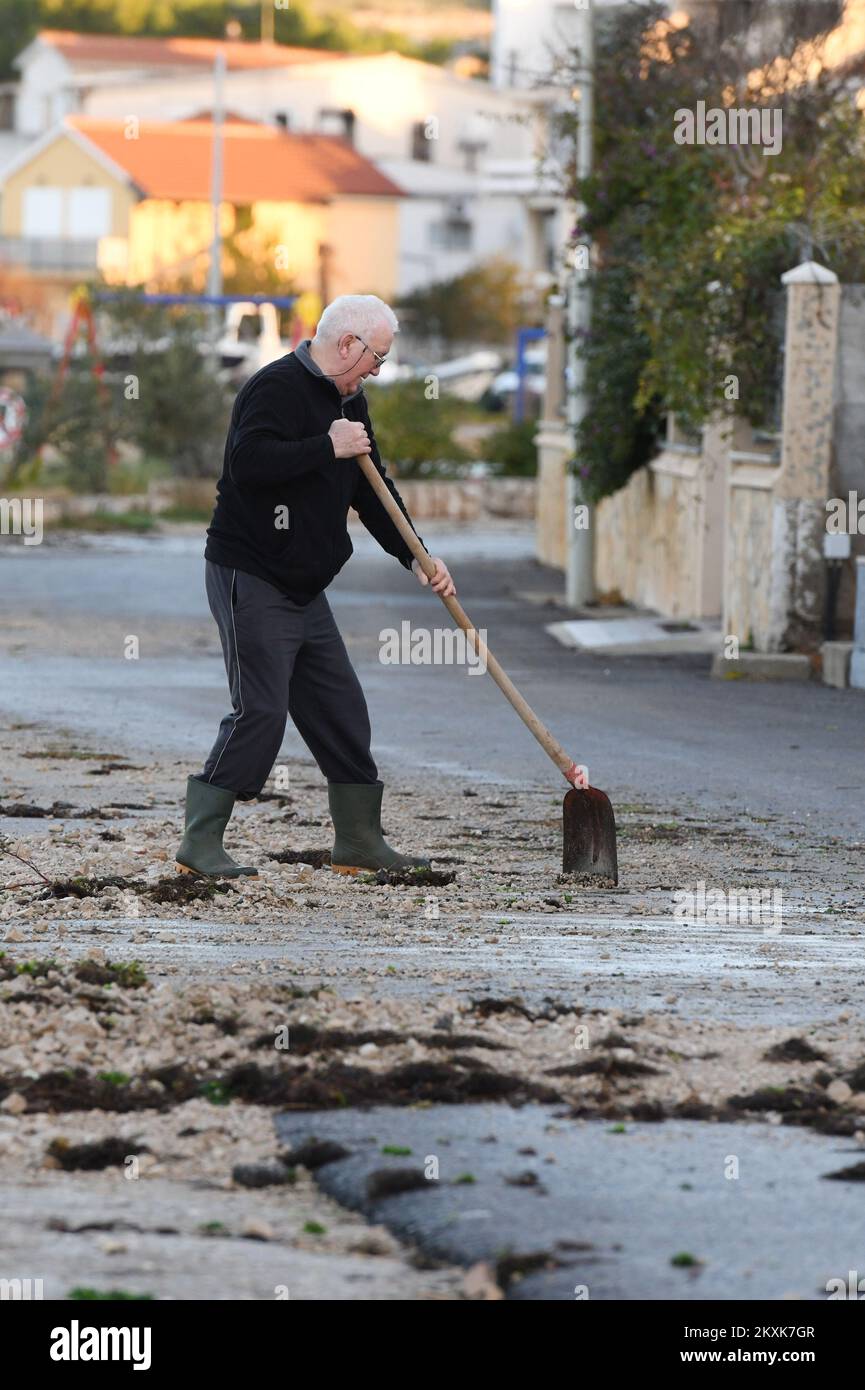 A man seen shoveling gravel and rocks thrown by the sea onto roads in ...