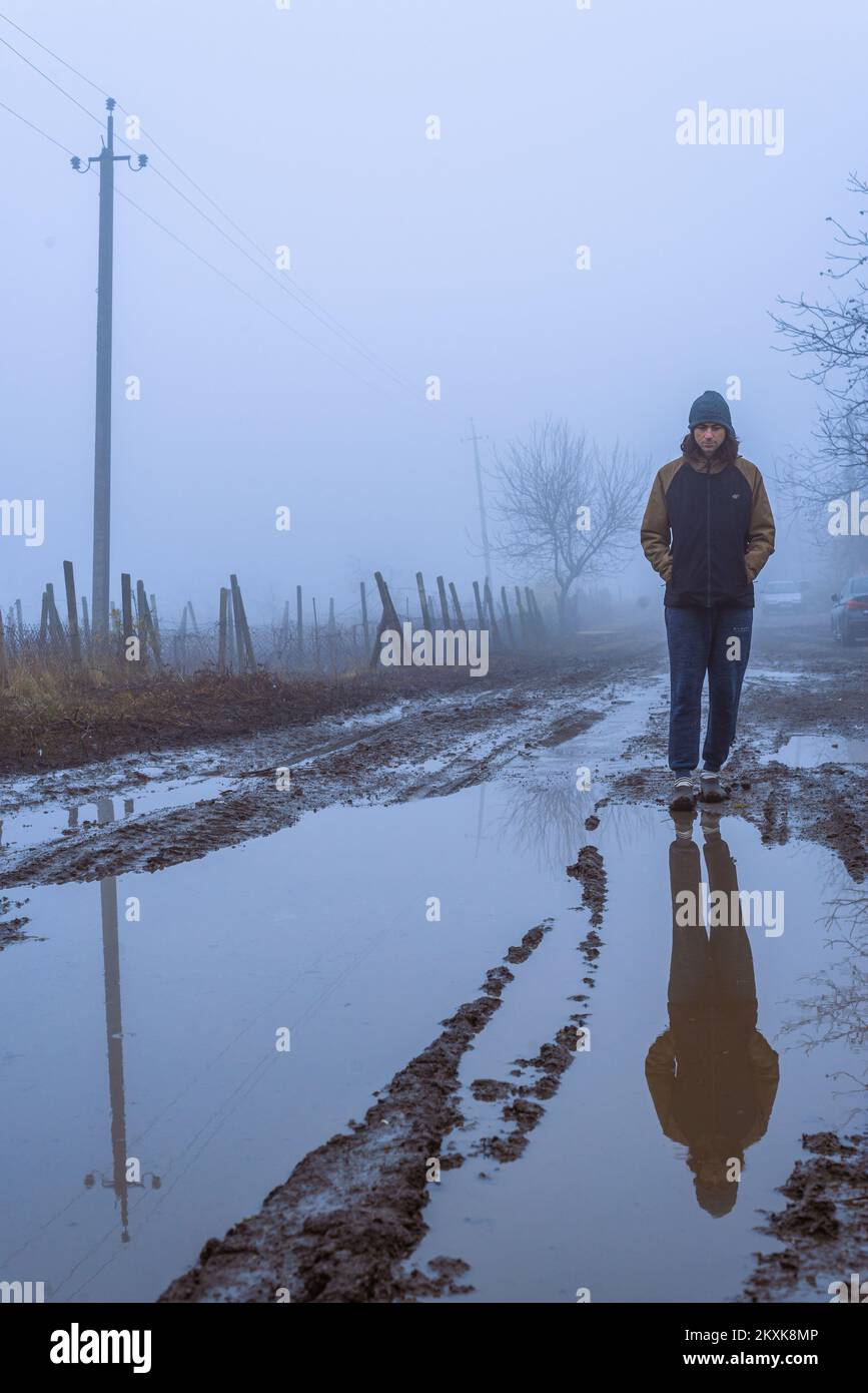 man walking dirt muddy road wet Puddle countryside street autumn fall ...