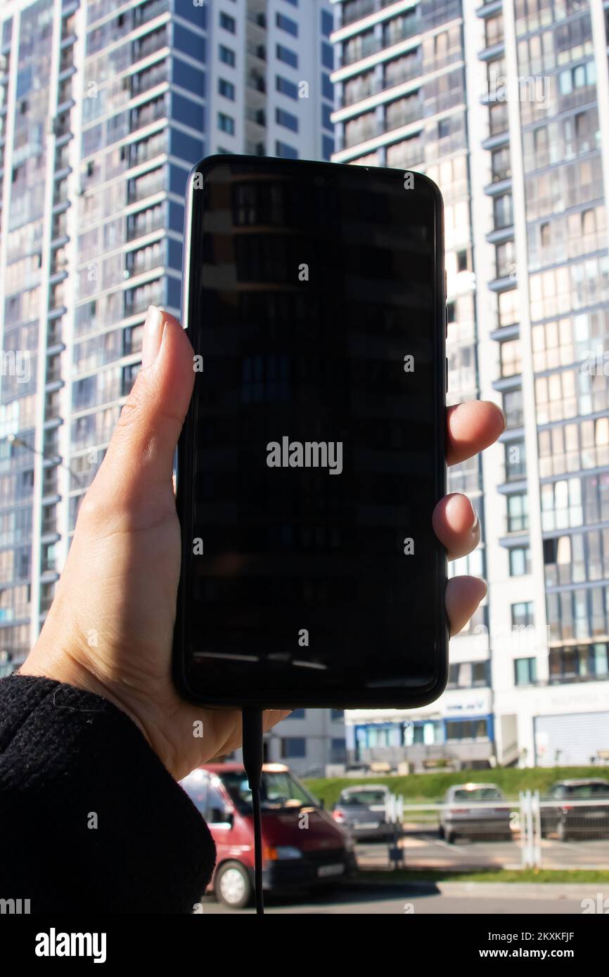 A phone in your hand against the backdrop of tall modern buildings ...
