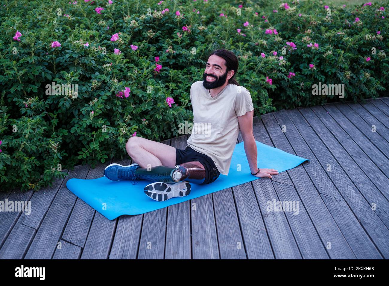 Young man with a prosthetic leg doing stretching exercises outdoors ...