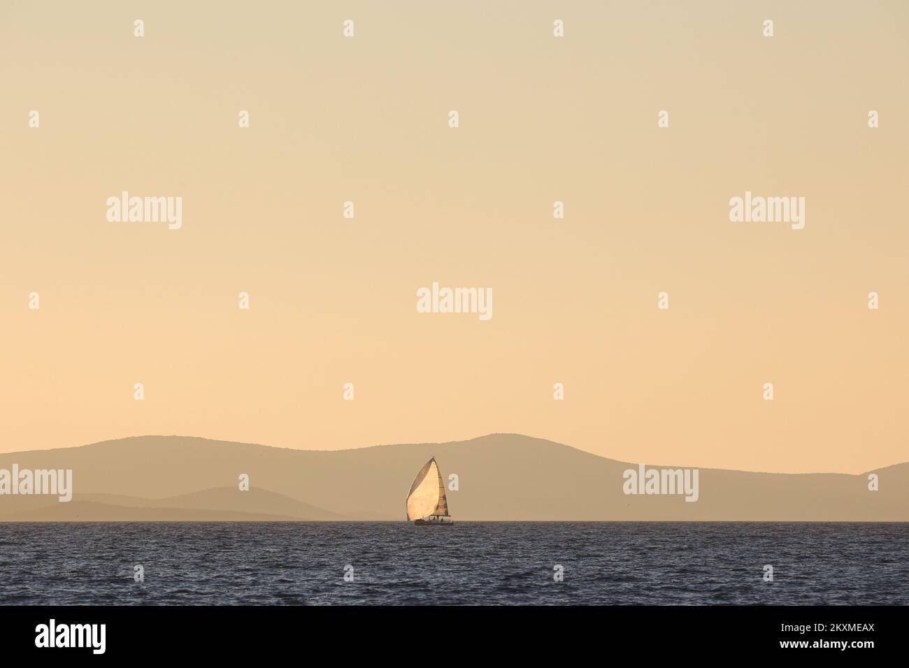 The Sun sets behind the Croatia-flagged sailboat as it sails in the ...