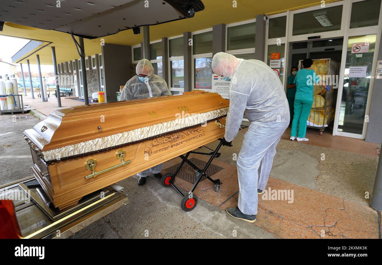 Funeral workers wearing protective suits move the coffin containing the ...