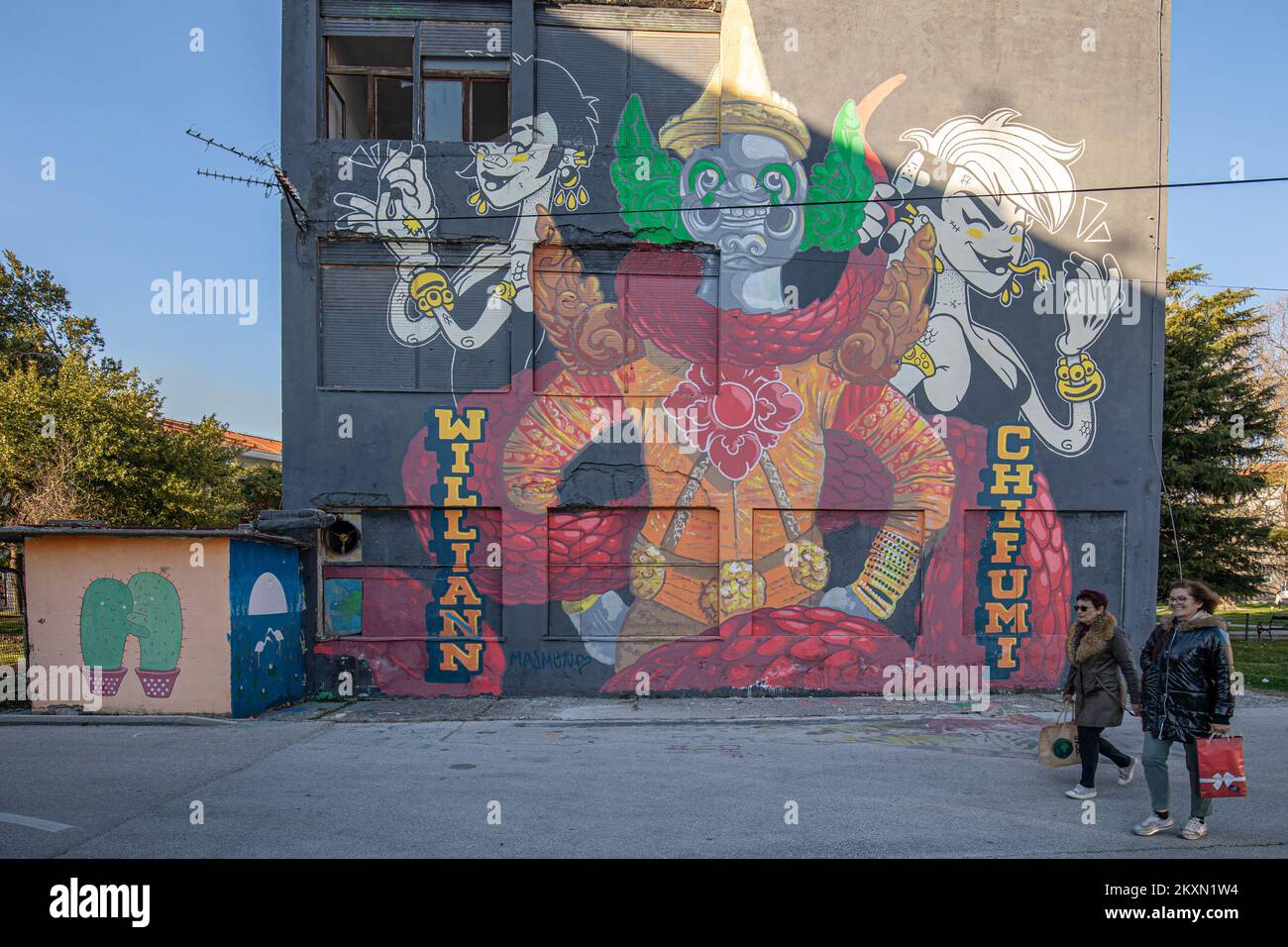 A women walk past graffiti on a wall as part of "Zen Opuzen" art ...