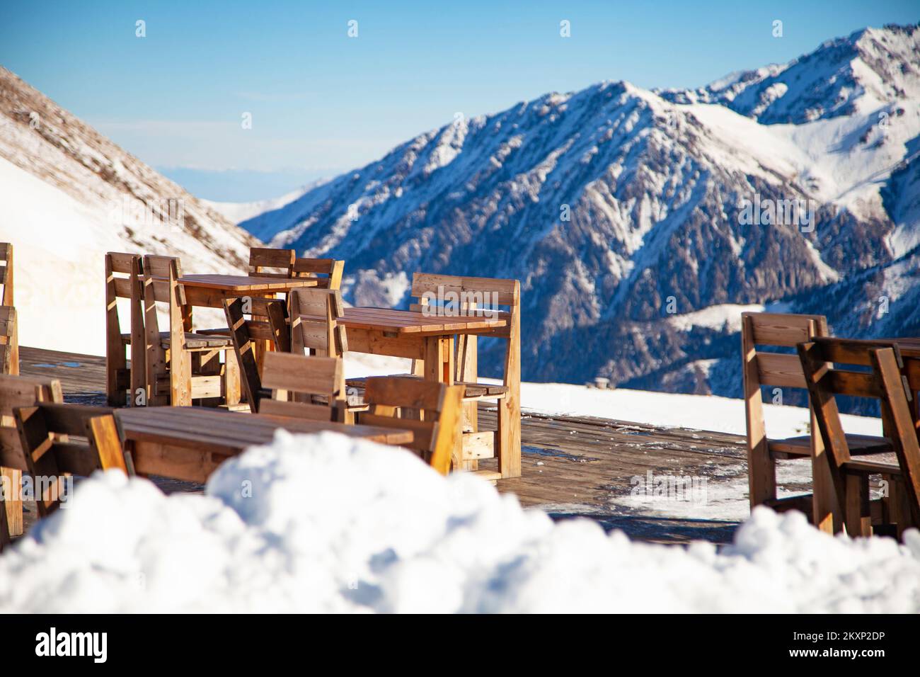 Outdoor restaurant terrace on top of a snowy mountain with wooden ...