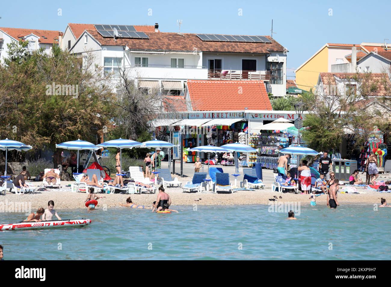People enjoy sunbathing and swimming at the beach, in Vodice, Croatia ...