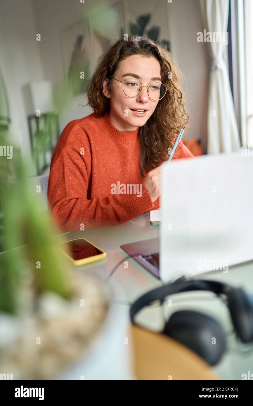 Young woman student elearning or having hybrid virtual meeting at home ...