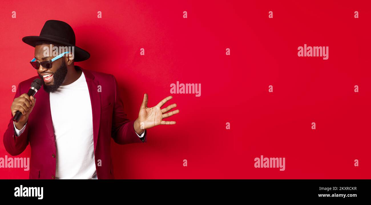 Passionate black male singer performing against red background, singing ...
