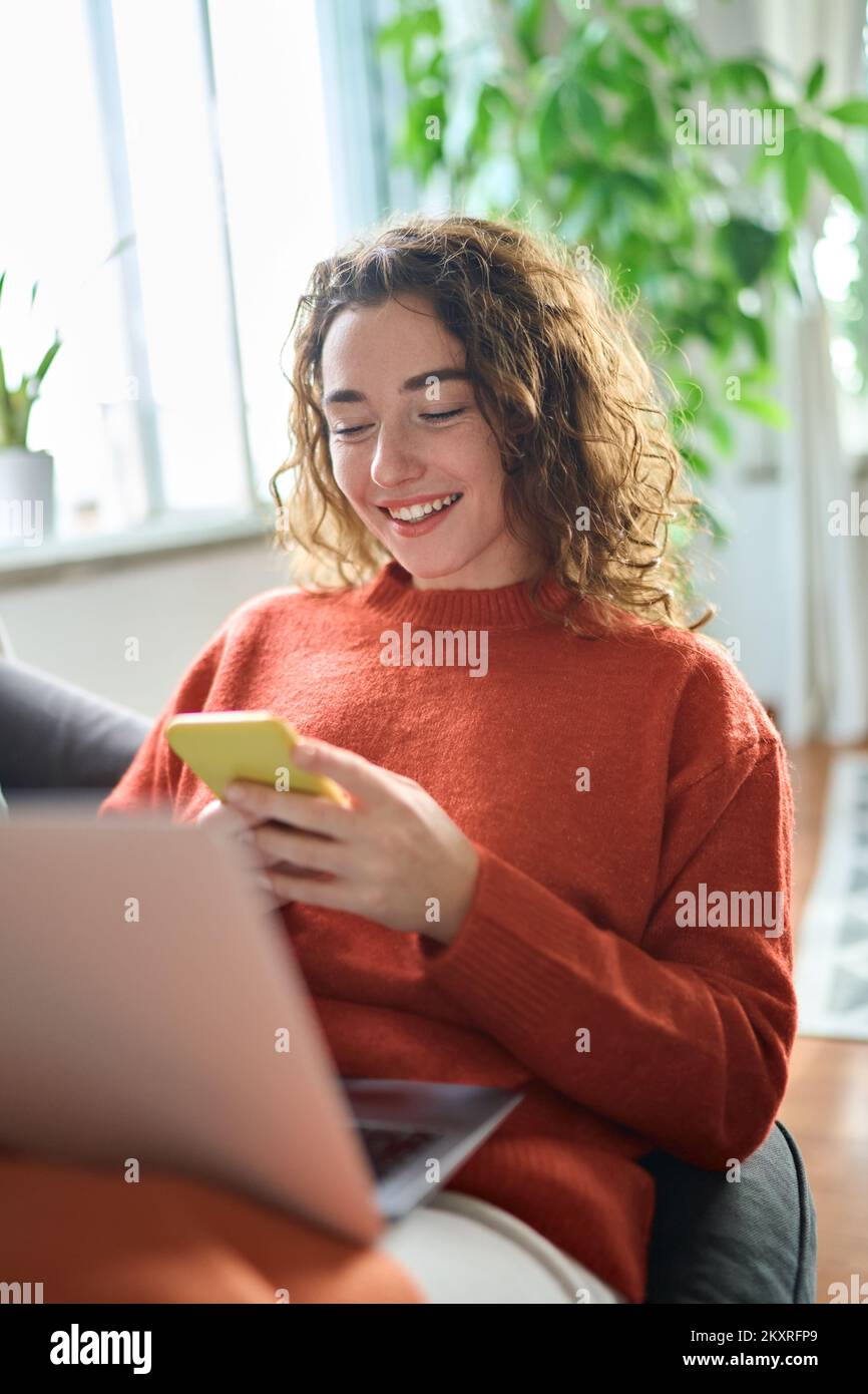 Happy young woman relaxing on couch using phone in cozy living room ...