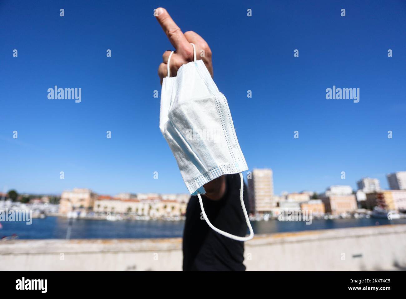 A man outside holding middle finger up with mask in Zadar, Croatia on ...