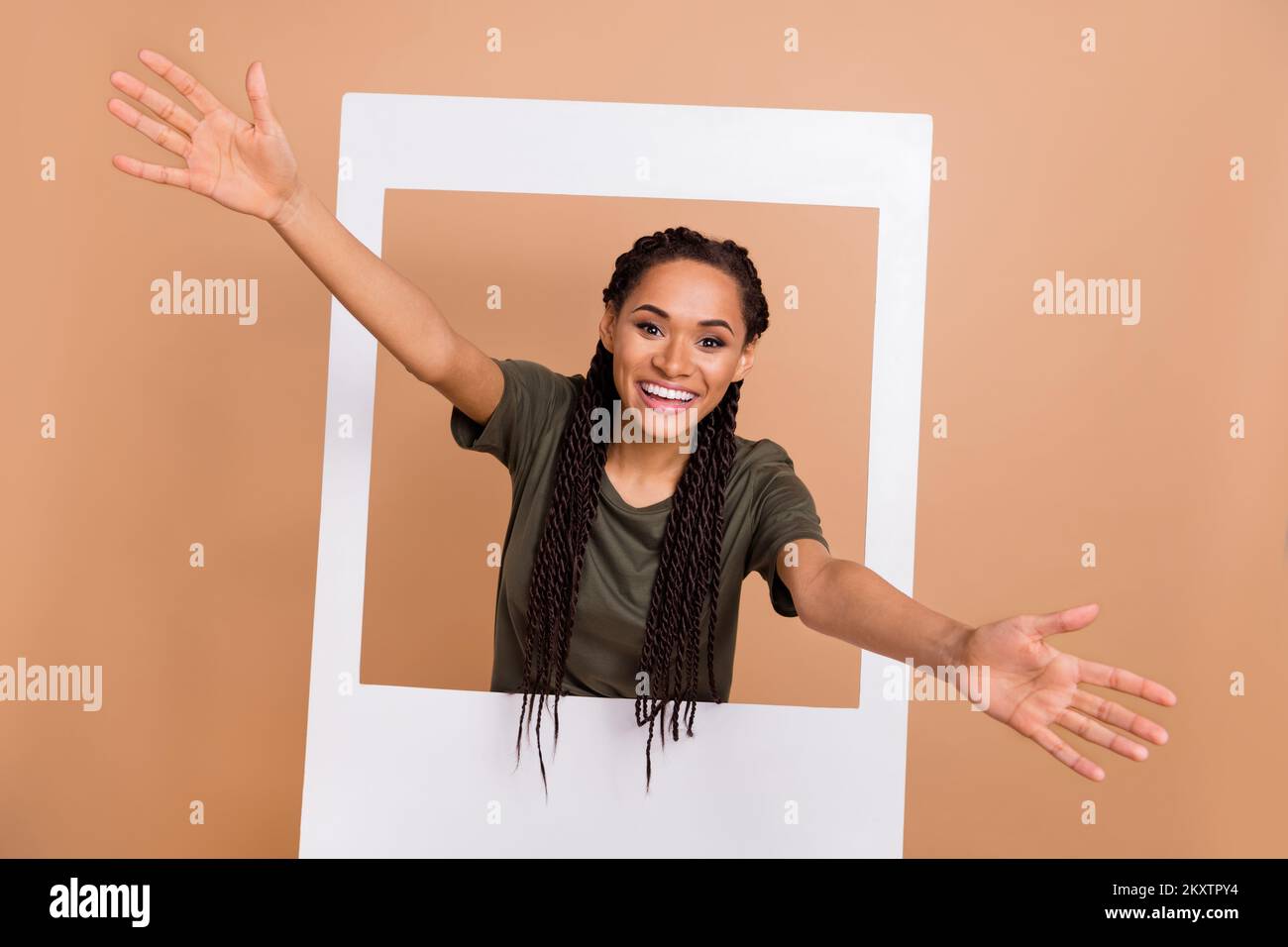 Photo of cheerful pretty person raise opened arms through paper window ...