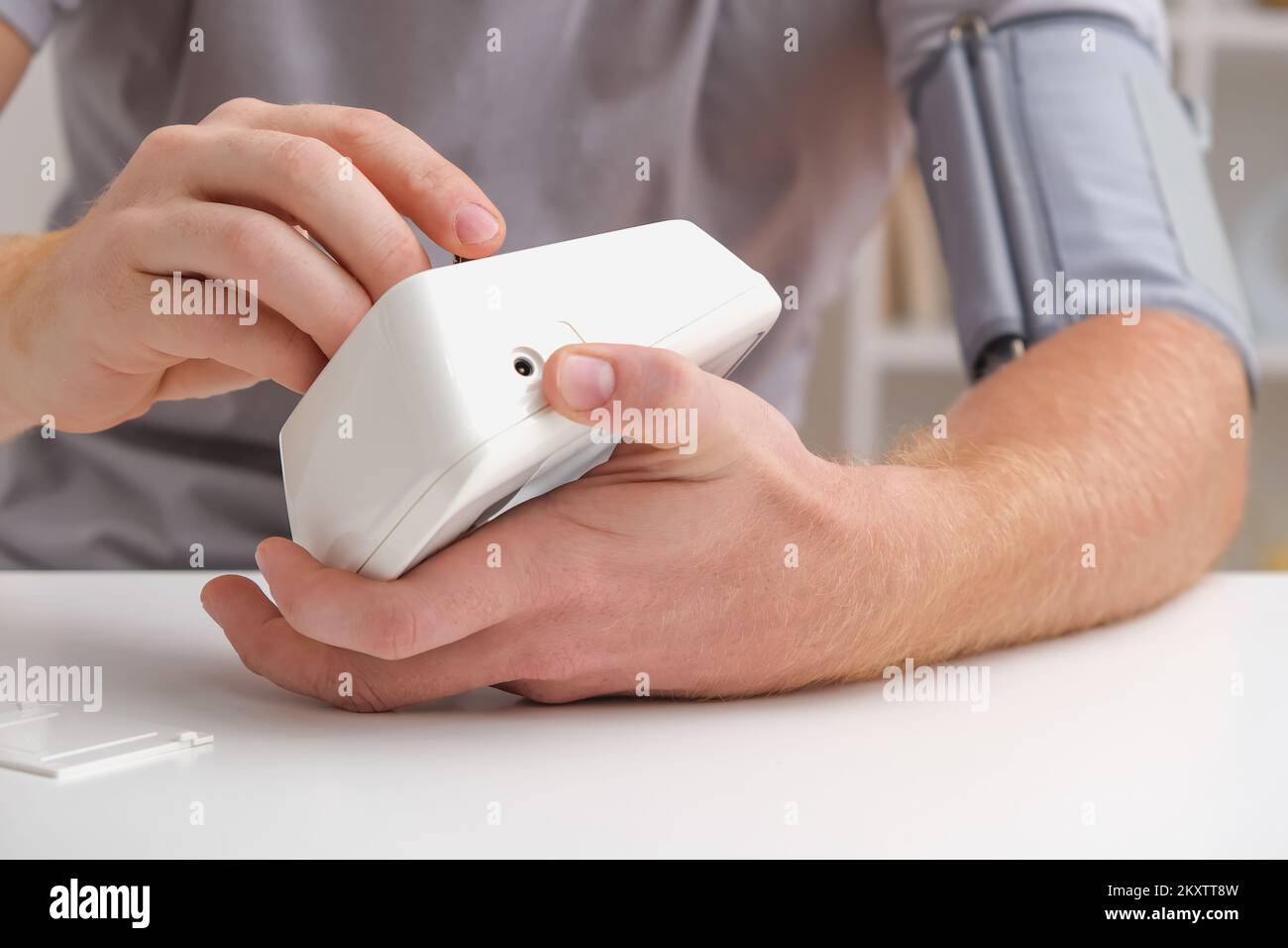 A man measures blood pressure with a white electric tonometer lying on ...