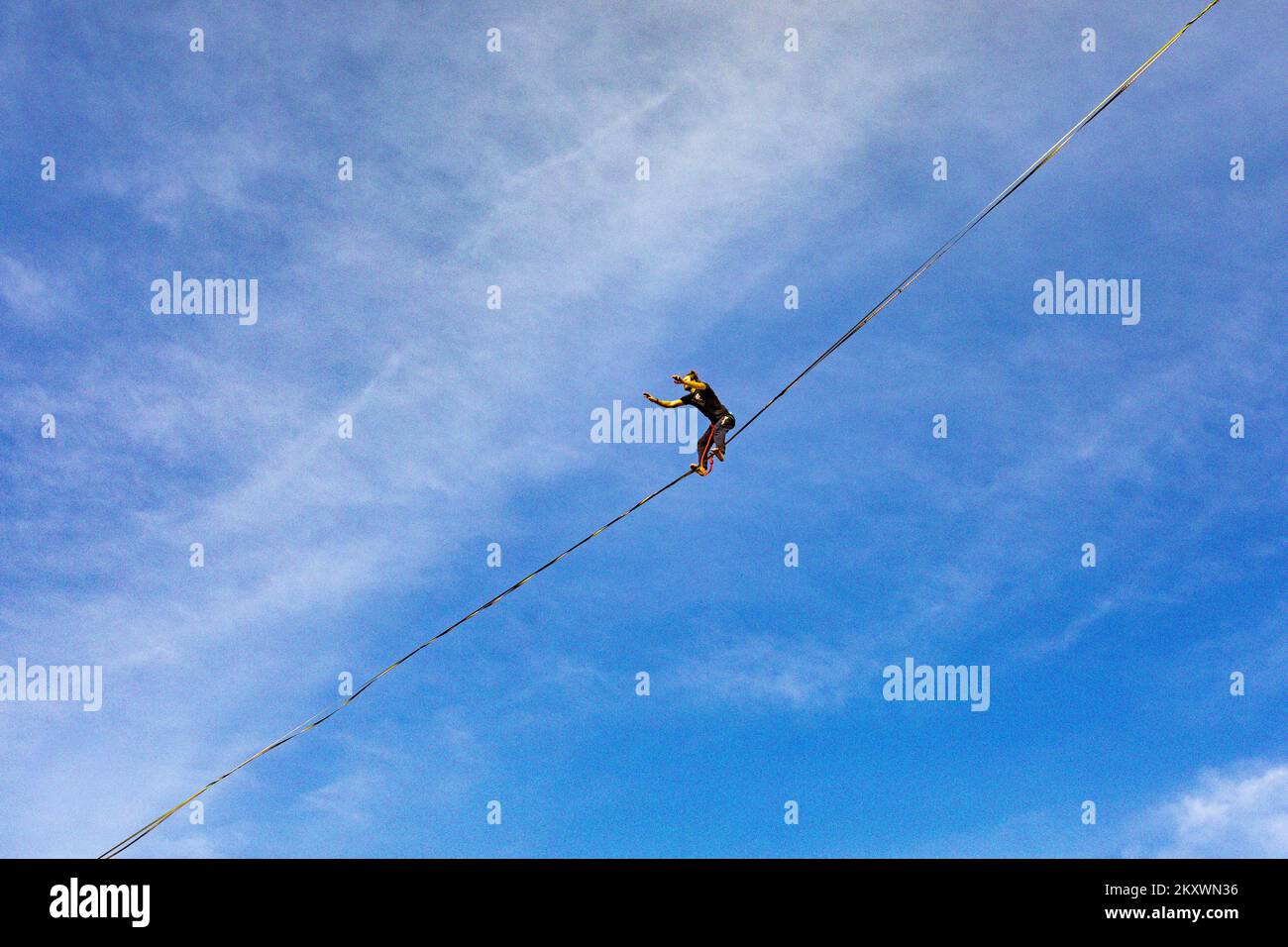 A slackline runner hangs on a rope between the two skyscrapers in Pula ...