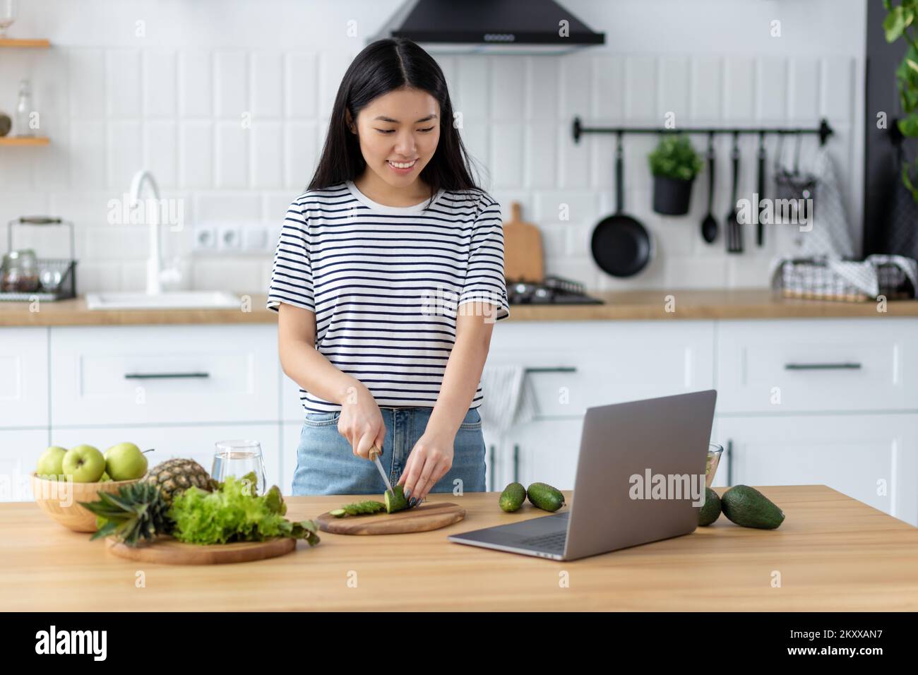 Cooking healthy food. Young asian woman watching recipe online using ...