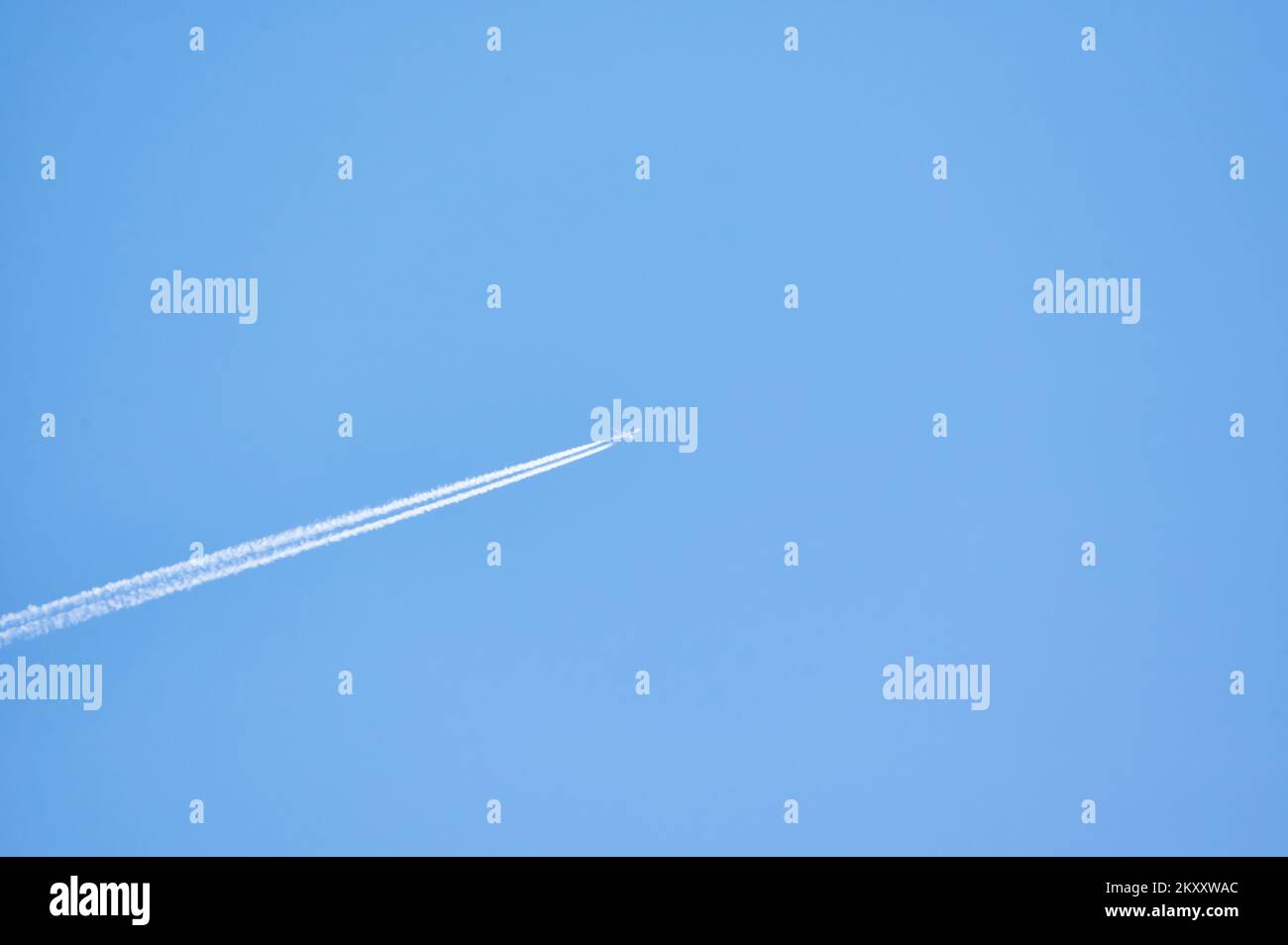 Plane flying through a clear blue sky leaving a long trail behind Stock ...