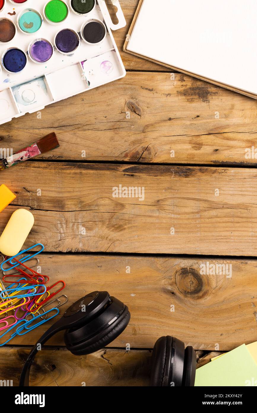 Composition of painting equipment and headphones on wooden background ...