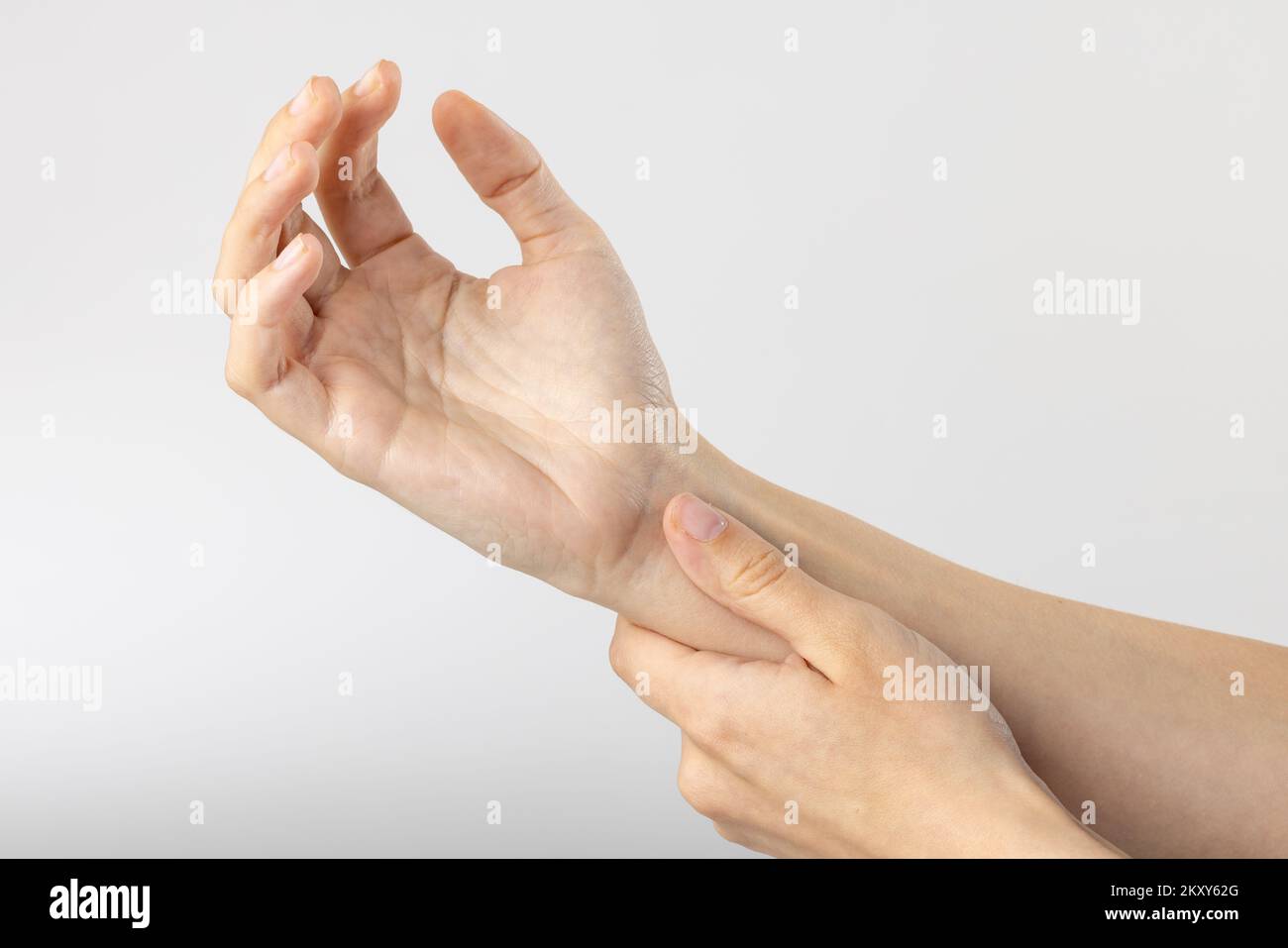 Close up of hands of caucasian woman taking pulse on wrist on white ...